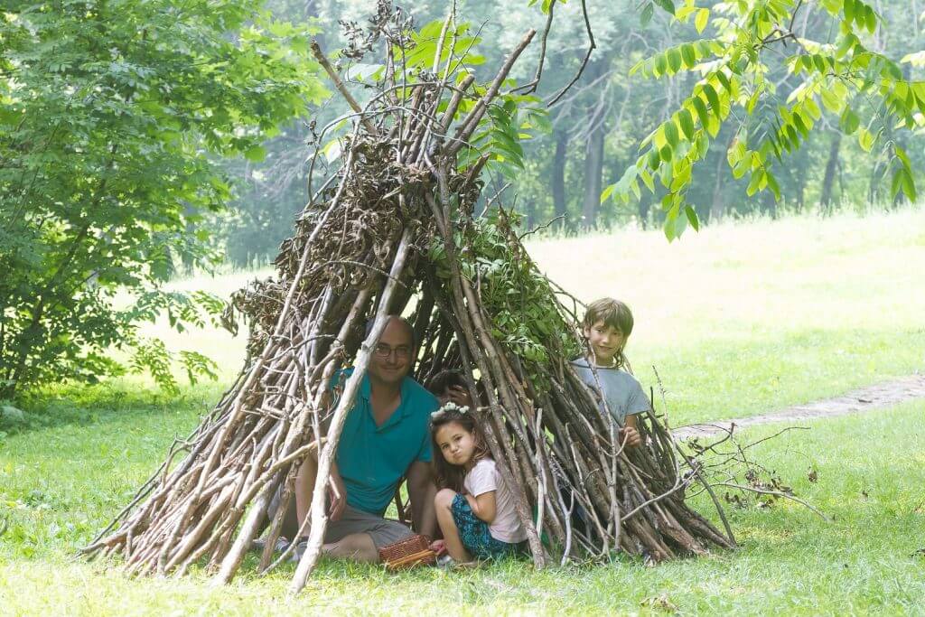 kids playing next to wooden stick house looking like indian hut,